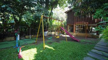 Um parquinho com balanços, escorrega e uma rede de escalada.