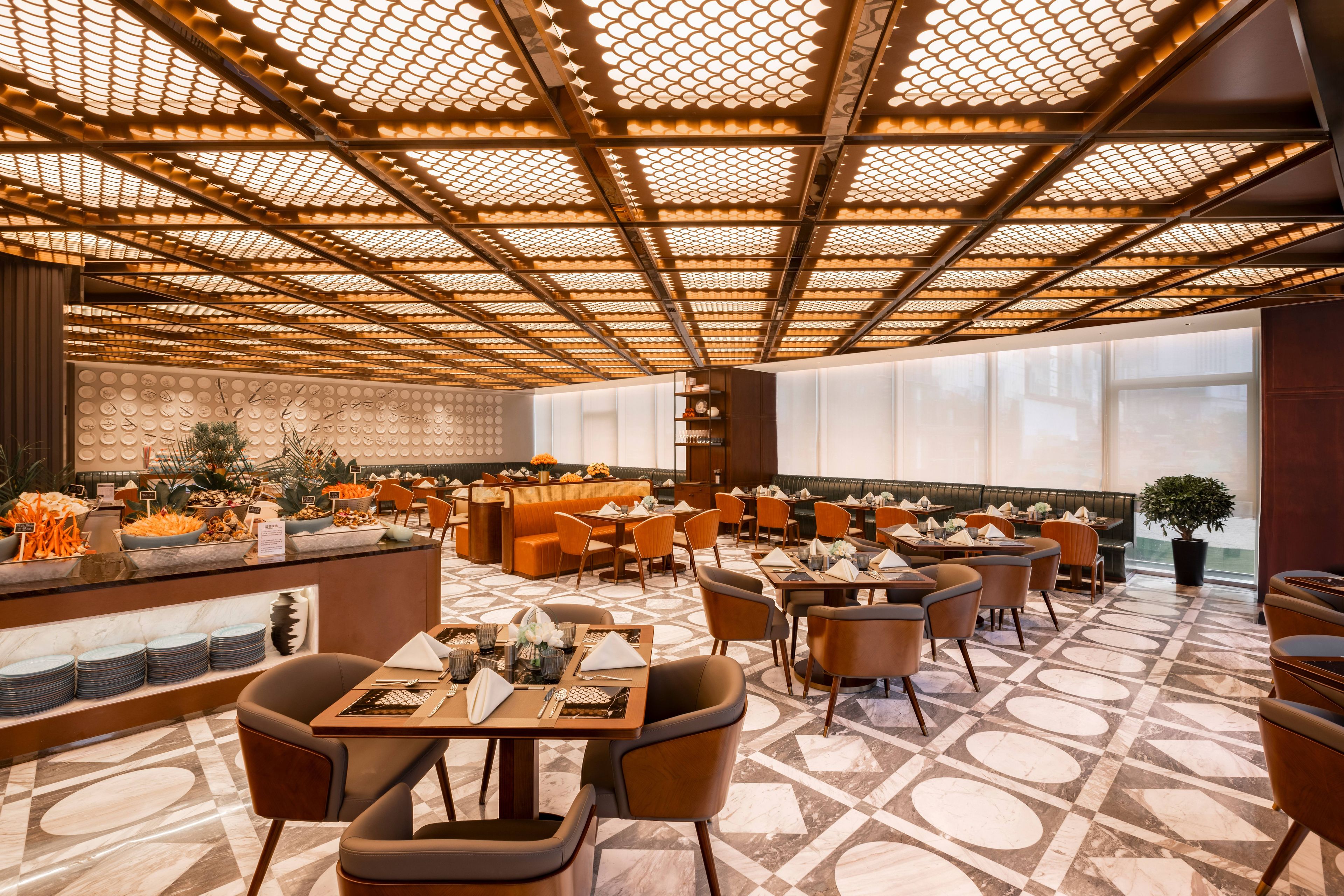 Restaurante com teto estampado, área de buffet e disposição de mesas e cadeiras.