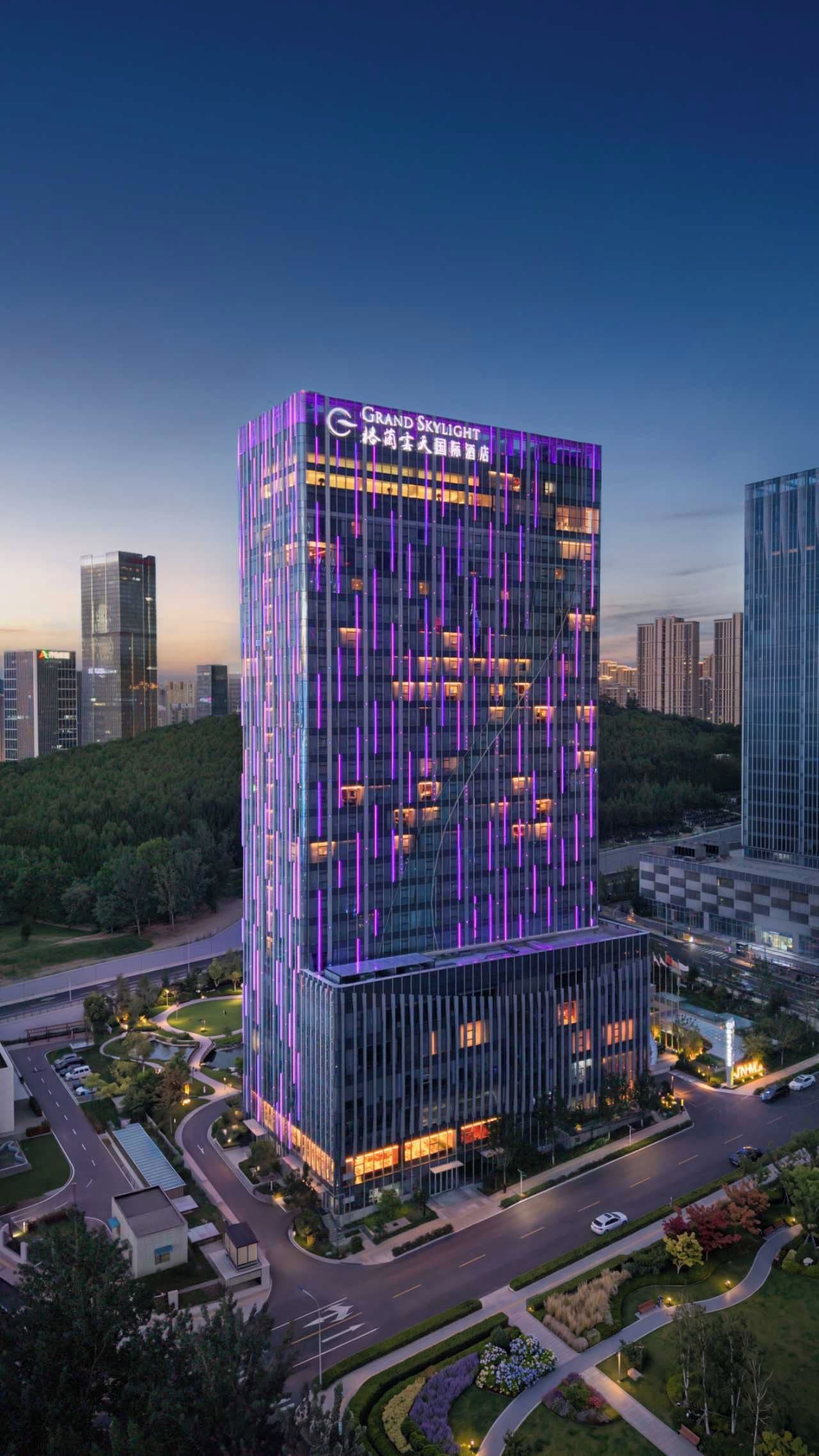 Um edifício moderno de arranha-céu com um design de iluminação vertical marcante, rodeado por um paisagismo urbano bem cuidado.