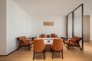 Uma sala de reuniões moderna com uma mesa redonda, seis cadeiras e decoração minimalista.