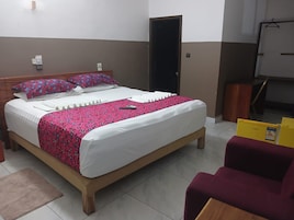 Quarto de hotel com cama, escrivaninha e cadeira.
