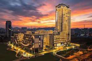Um moderno edifício alto com janelas iluminadas e uma entrada imponente.
