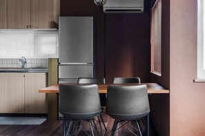 Uma cozinha moderna com geladeira embutida, mesa de jantar com cadeiras e uma janela com persianas.
