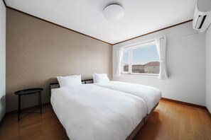 Quarto de hotel com uma cama grande, uma mesa pequena e uma janela com cortinas.