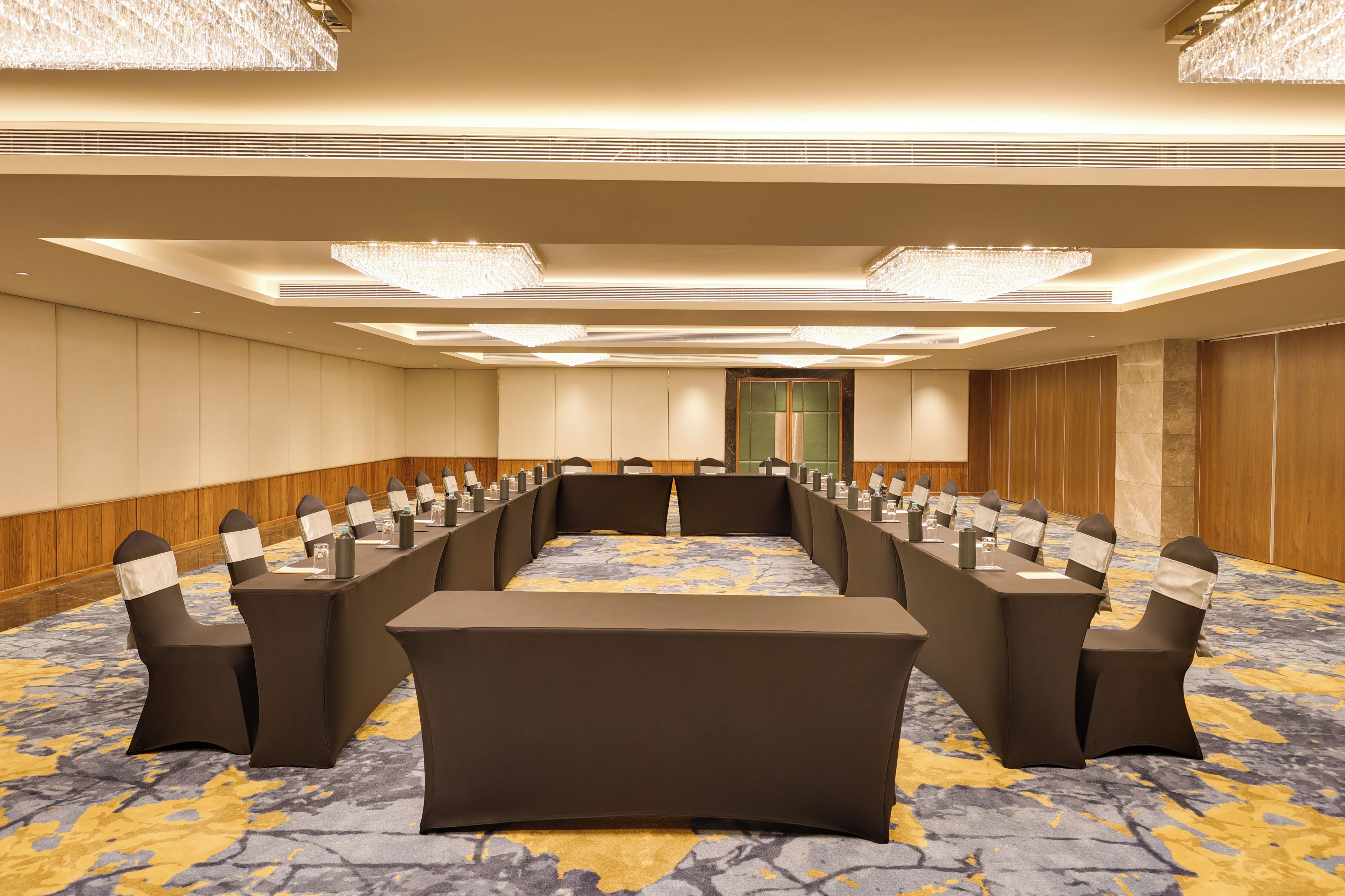Sala de conferência com uma mesa comprida, cadeiras e piso coberto por carpete.