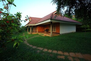 Uma casa com telhado de cerâmica, varanda e um caminho que leva à entrada.