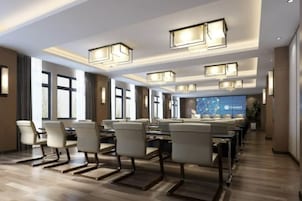 Sala de conferências com uma mesa comprida, cadeiras e tela de projeção.