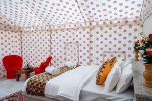 Quarto com cama, uma cadeira vermelha, uma mesinha e parede com padrão.