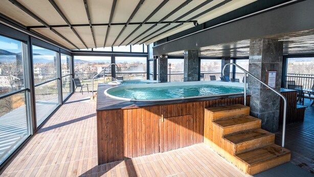 Piscina interior moderna com deck de madeira e vista para a cidade.