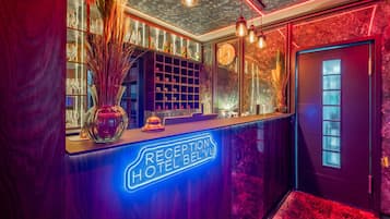 Uma área de recepção com um letreiro de neon, prateleiras com copos e uma porta com janela.