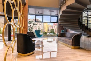 Um lobby moderno com escadaria, área de estar e grandes janelas com vista para a cidade.