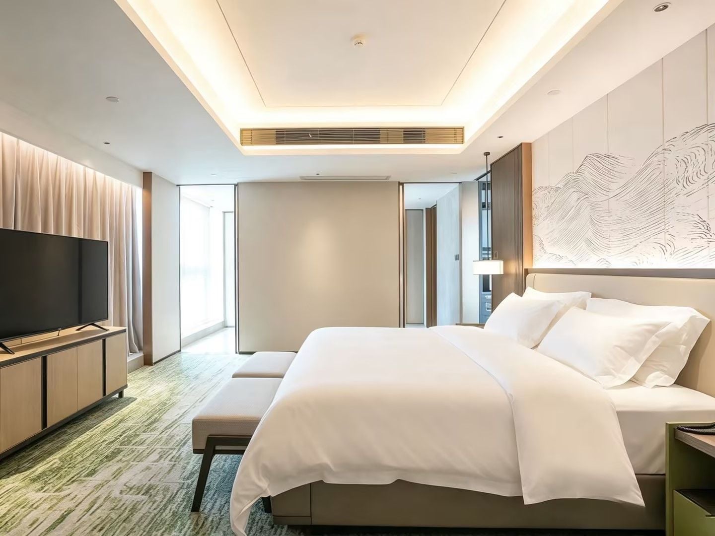 Quarto de hotel com cama grande, televisão de tela plana, escrivaninha e obra de arte na parede.