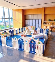 Espaço infantil com escorrega, tapetes de brincar e piscina de bolinhas.