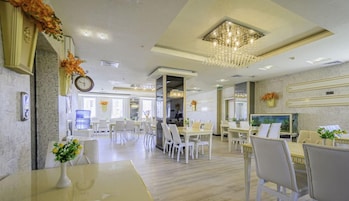 Espaço de refeições de hotel com várias mesas e cadeiras, um candelabro e um relógio na parede.
