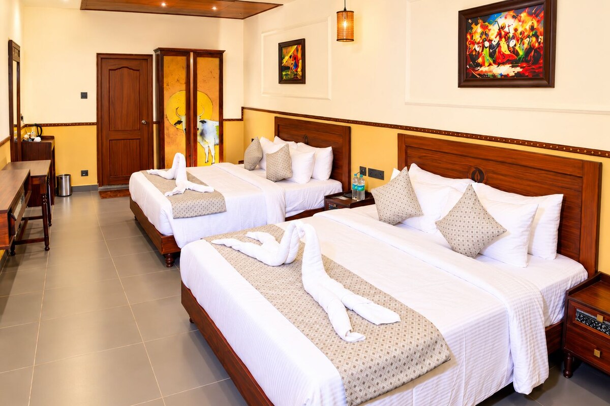 Quarto de hotel com duas camas, uma escrivaninha e uma cadeira.