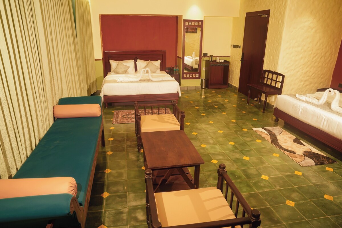 Quarto de hotel com cama, sofá, mesa e cadeira.