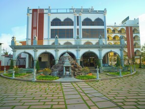 Um hotel com um pátio central, várias arcadas e uma fonte.