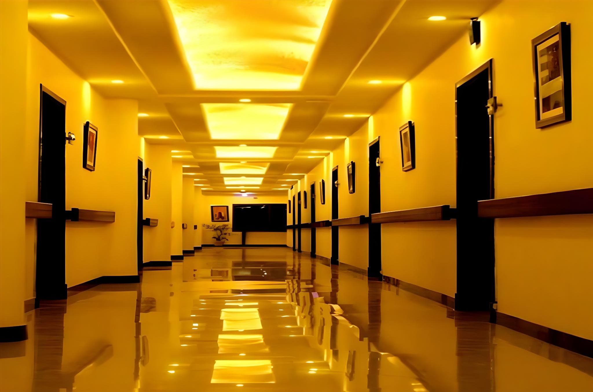 Corredor longo e bem iluminado, com portas em ambos os lados, que dá acesso a quartos.