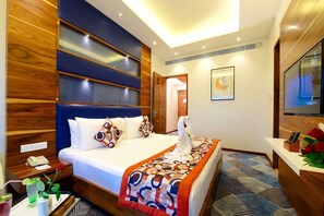 Quarto de hotel com cama, mesa de cabeceira e escrivaninha com telefone.