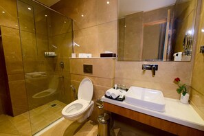 Uma casa de banho moderna com cabine de duche em vidro, sanita branca e toucador com espelho.