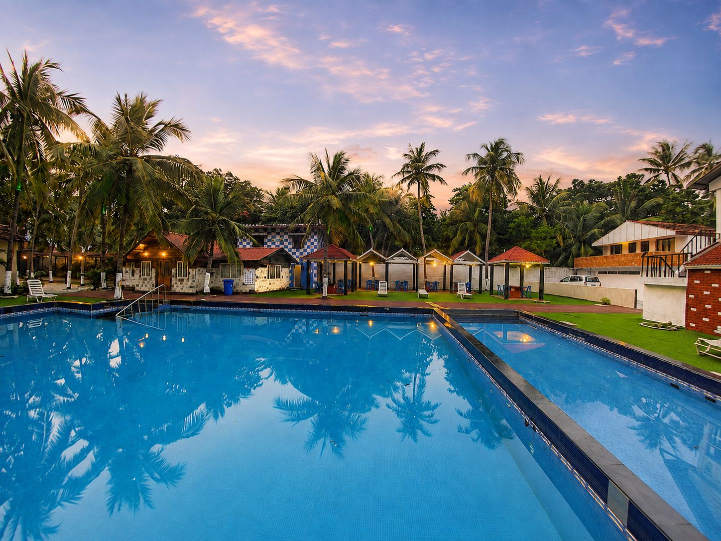 Piscina com espreguiçadeiras e palmeiras.