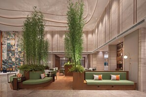 Um hall amplo com pé direito alto, móveis modernos e jardins verticais.