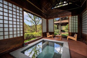Um quarto em estilo japonês tradicional, com tatames, uma pequena mesa de madeira e um espaço de estar com tatames.