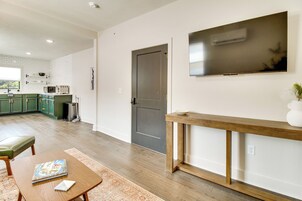 Cozinha moderna com azulejos brancos tipo metrô, área de jantar com mesa de madeira e um livro, e porta cinza.