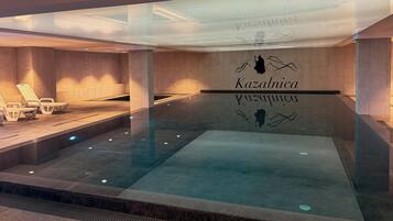 Área da piscina com espreguiçadeiras e uma parede com o nome 'Kazahica'.