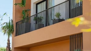 Um edifício moderno com varanda, janela e algumas plantas.