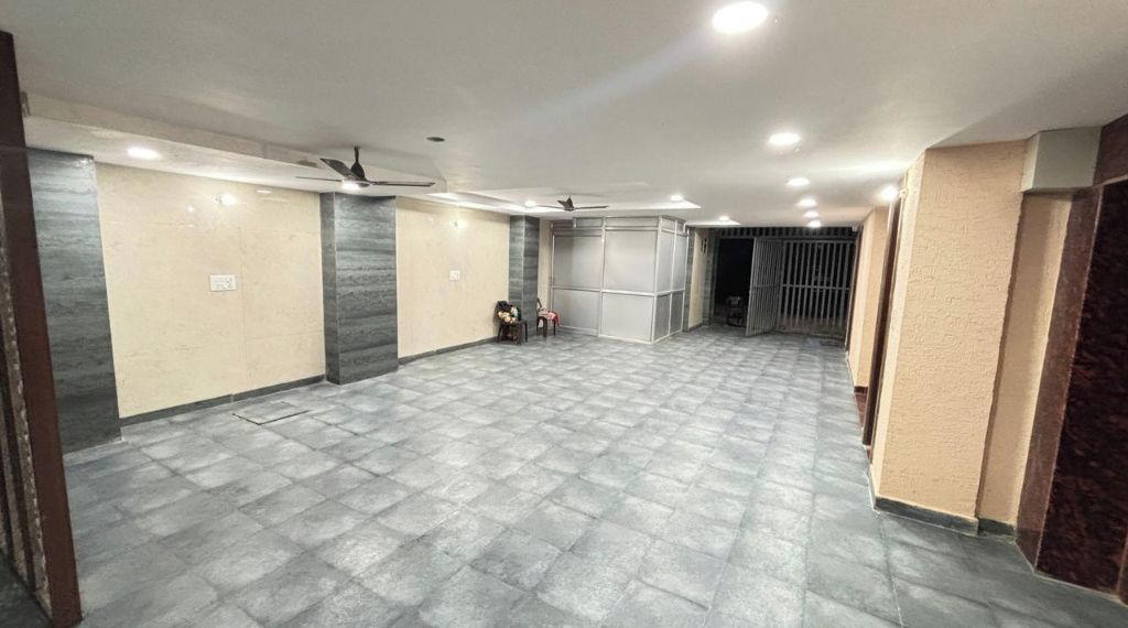 Quarto amplo com piso de azulejos, ventilador no teto e porta que dá para outra área.