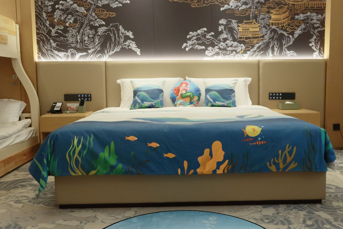 Quarto de hotel com cama, mesa de cabeceira, escrivaninha e cadeira.