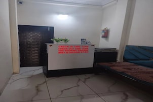 Balcão de recepção com placa indicando horários de entrada e saída, telefone e uma pequena planta.