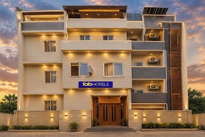 Um hotel de vários andares com design moderno, com varandas, aparelhos de ar condicionado e uma placa chamativa da 'fabHOTELS'.