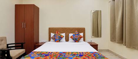 Quarto de hotel com cama, guarda-roupa, escrivaninha e cadeira.