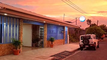 Um edifício com fachada azul, um veículo estacionado e céu claro.