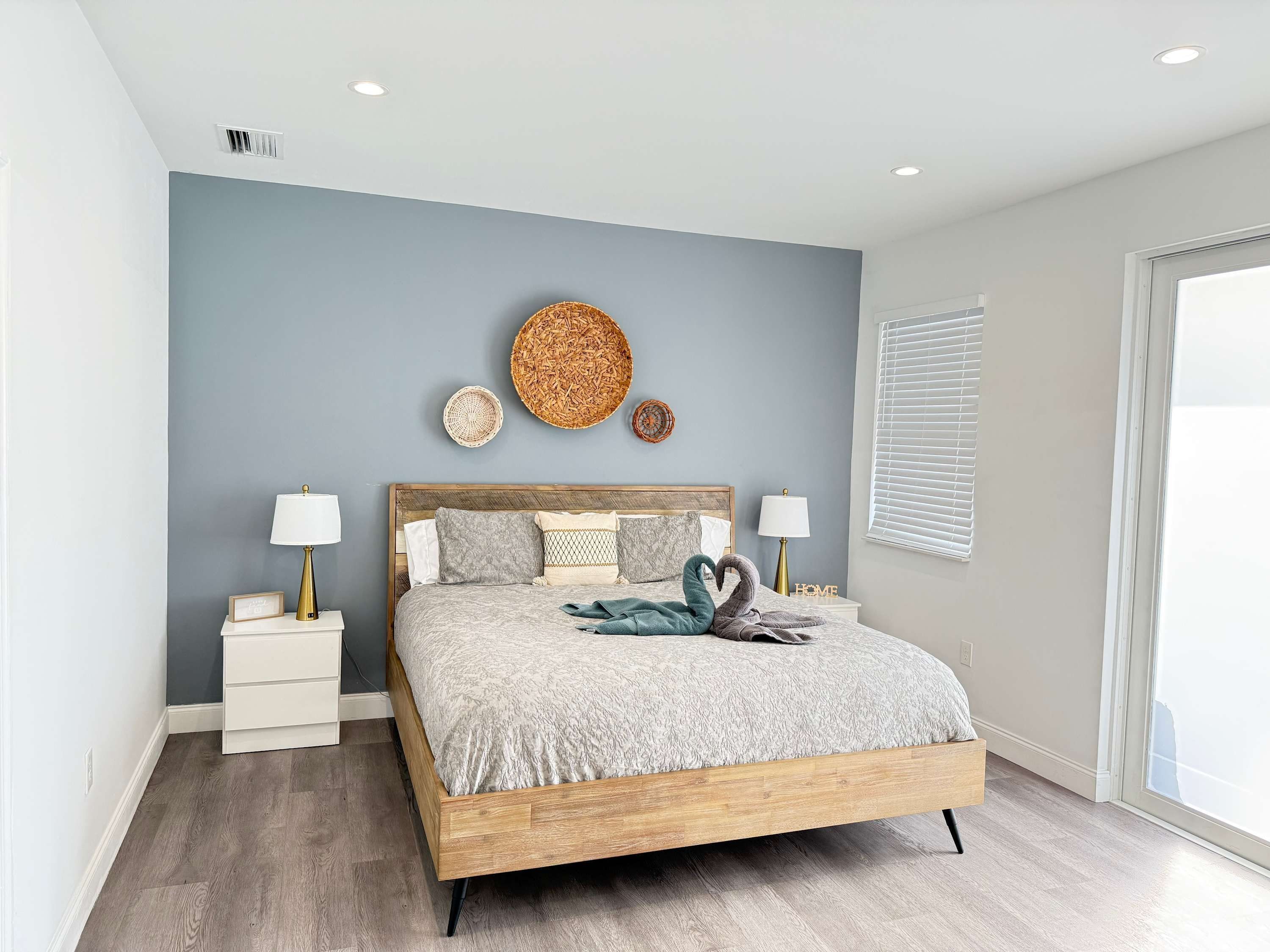 Quarto com cama, mesas de cabeceira, decoração na parede e uma janela.