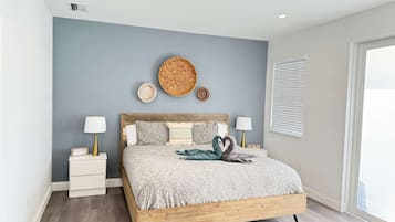 Quarto com cama, mesas de cabeceira, decoração na parede e uma janela.