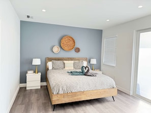 Quarto com cama, mesas de cabeceira, decoração na parede e uma janela.