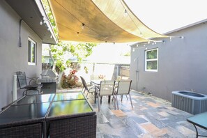 Uma área de pátio externa com mesa e cadeiras, churrasqueira e um espaço de estar coberto.