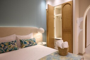 Quarto de hotel com cama, mesa de cabeceira, luminária, guarda-roupa e cesta de toalhas.