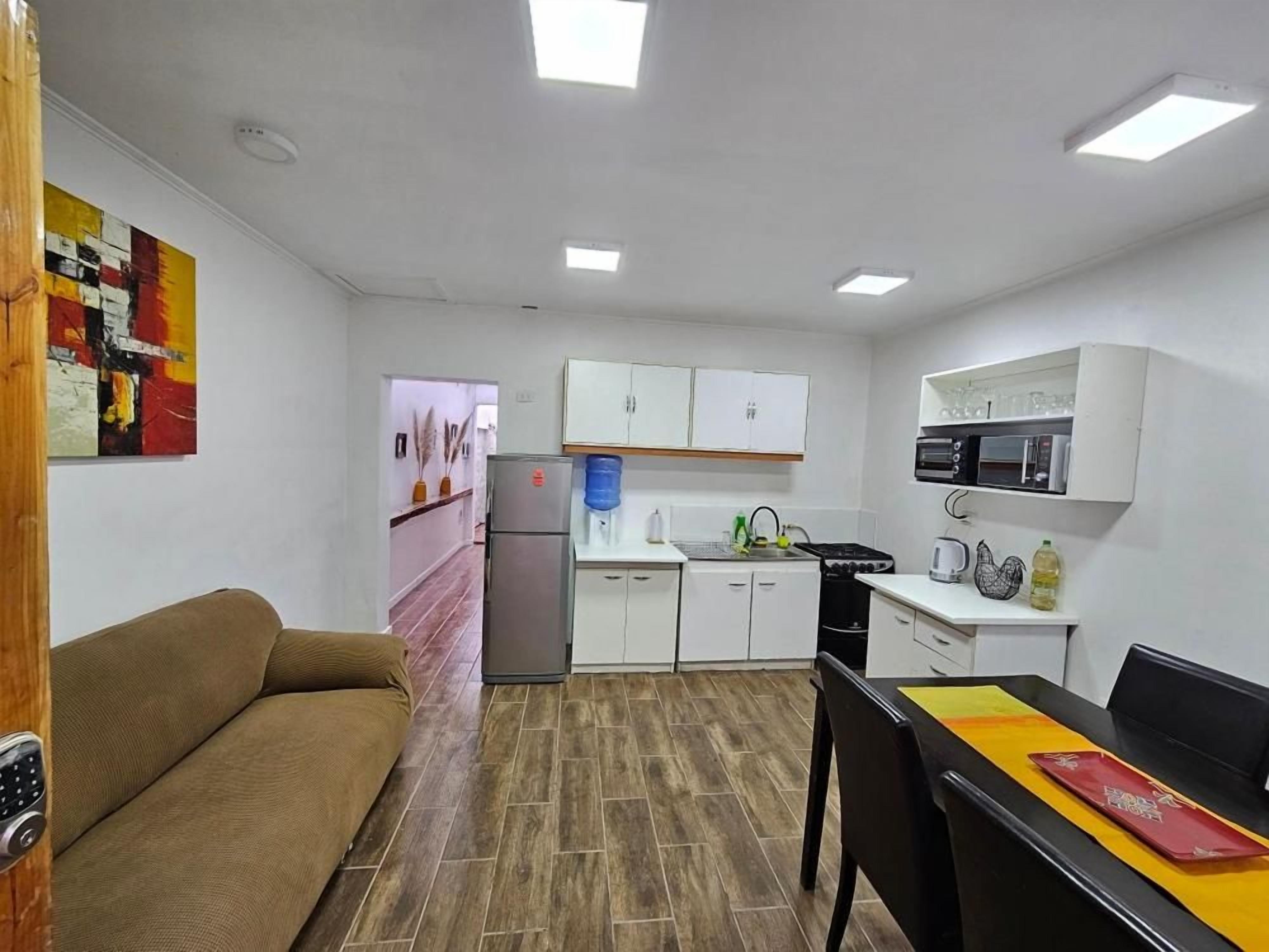 Espaço compacto com cozinha compacta, sofá, mesa de jantar e micro-ondas.