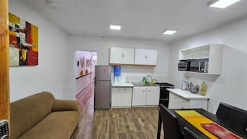 Espaço compacto com cozinha compacta, sofá, mesa de jantar e micro-ondas.