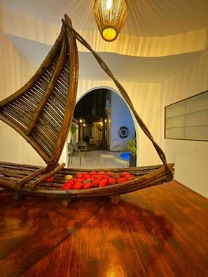 Quarto com uma cadeira suspensa singular repleta de objetos vermelhos, piso de madeira e luminária no teto.