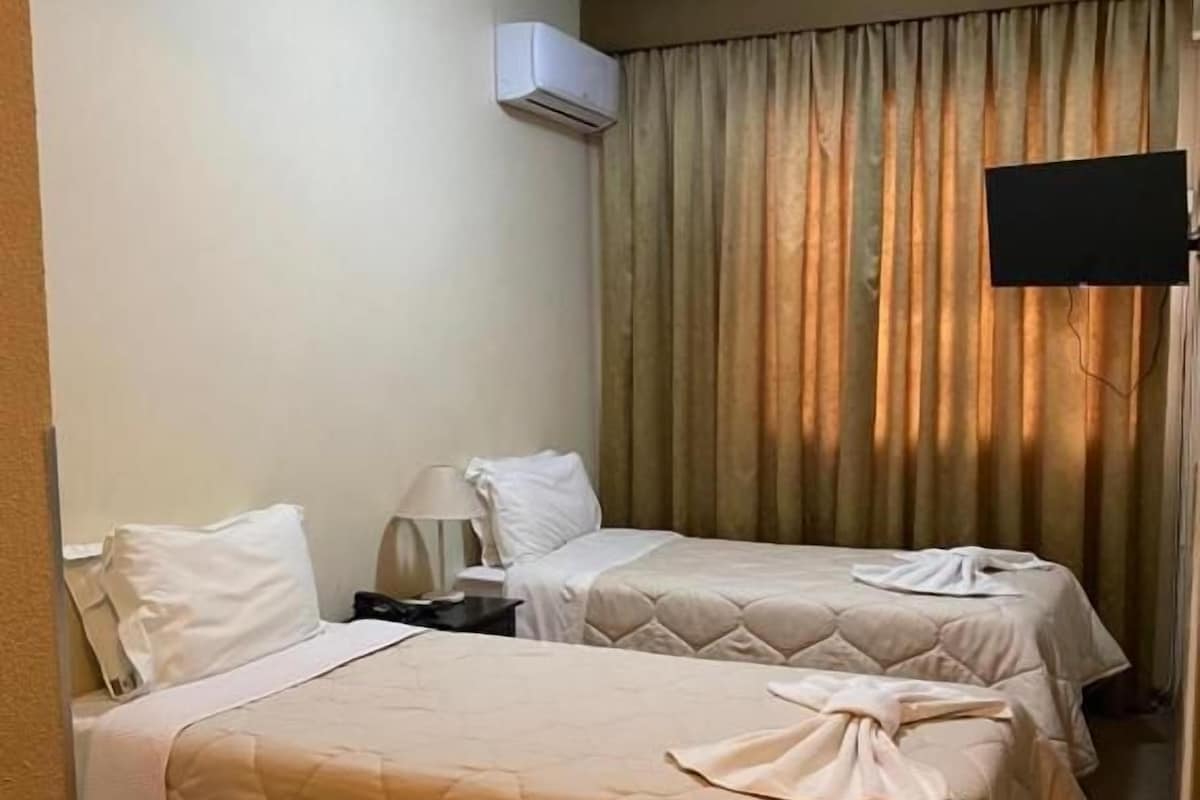 Quarto de hotel com duas camas, uma televisão de tela plana e ar condicionado.