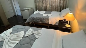 Quarto de hotel com duas camas, uma mesa de cabeceira com abajur e uma pequena escrivaninha com computador.