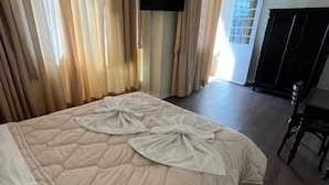 Quarto de hotel com cama grande, cortinas, TV de tela plana e lareira.