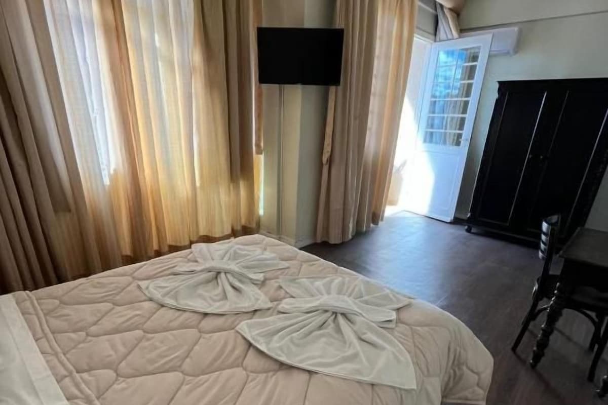 Quarto de hotel com cama grande, cortinas, TV de tela plana e lareira.