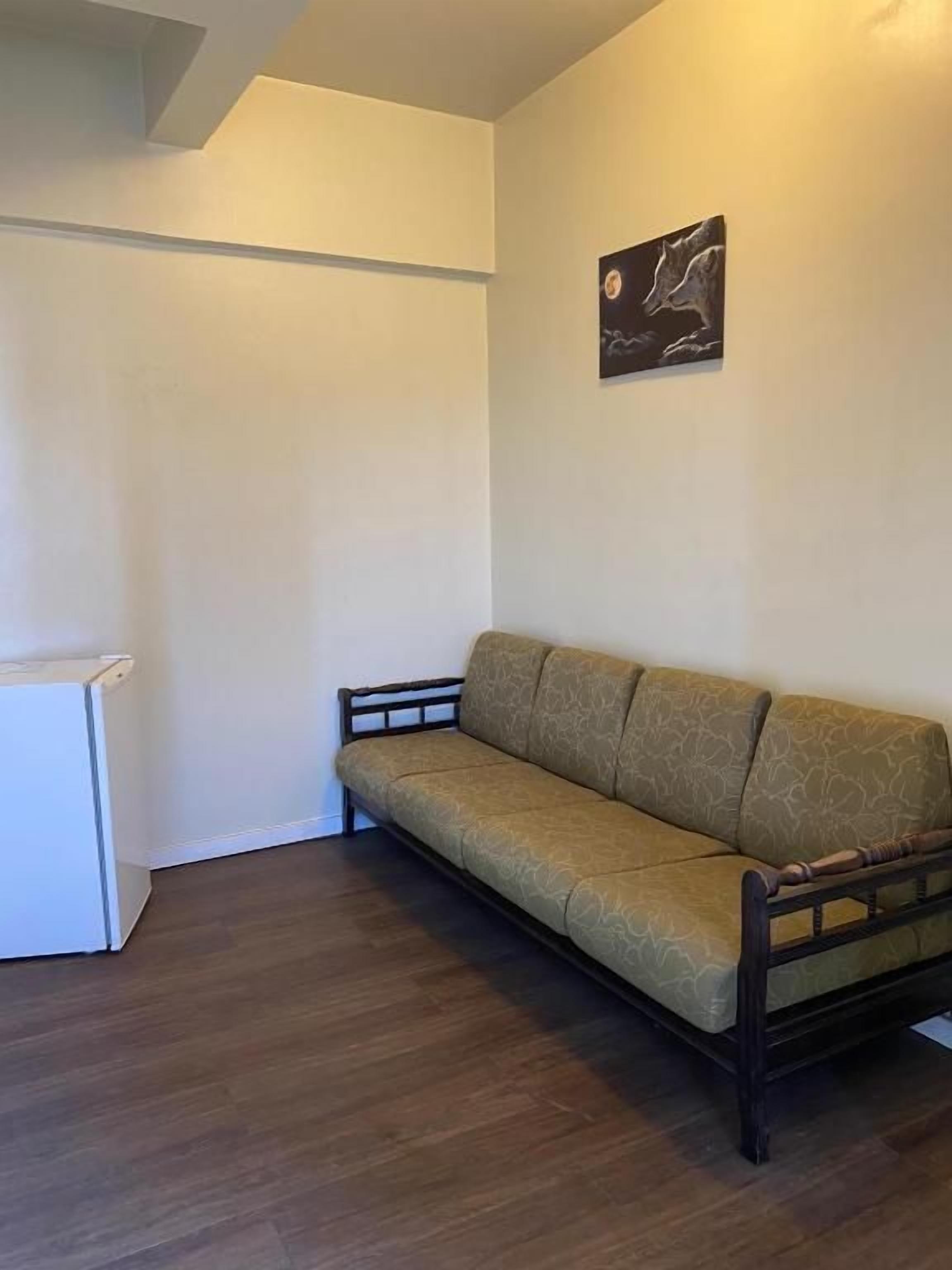 Quarto com sofá, uma pequena mesa branca e um quadro na parede.