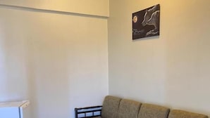 Quarto com sofá, uma pequena mesa branca e um quadro na parede.